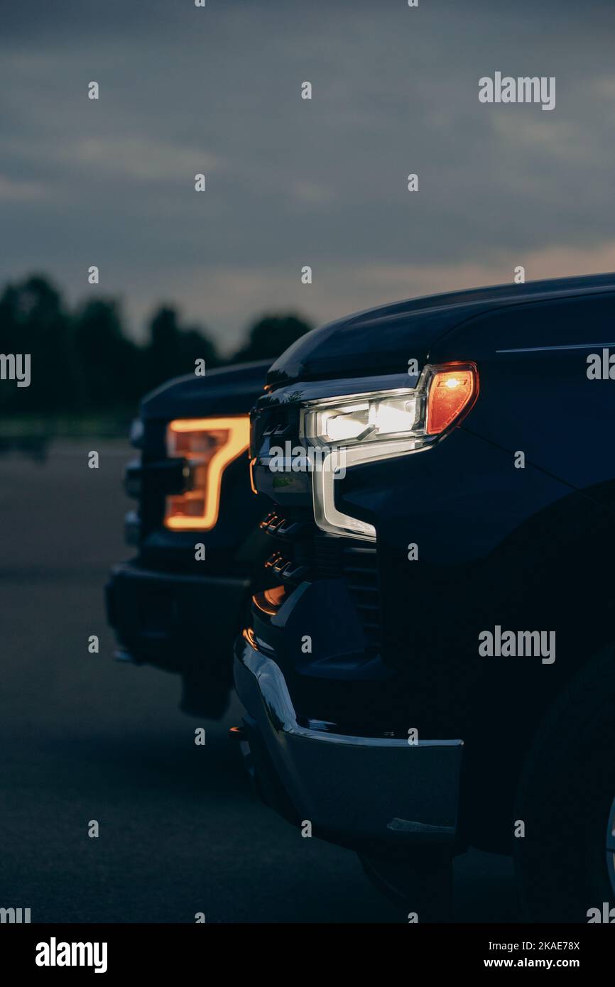 A vertical shot of two black cars with illuminated headlights on the ...