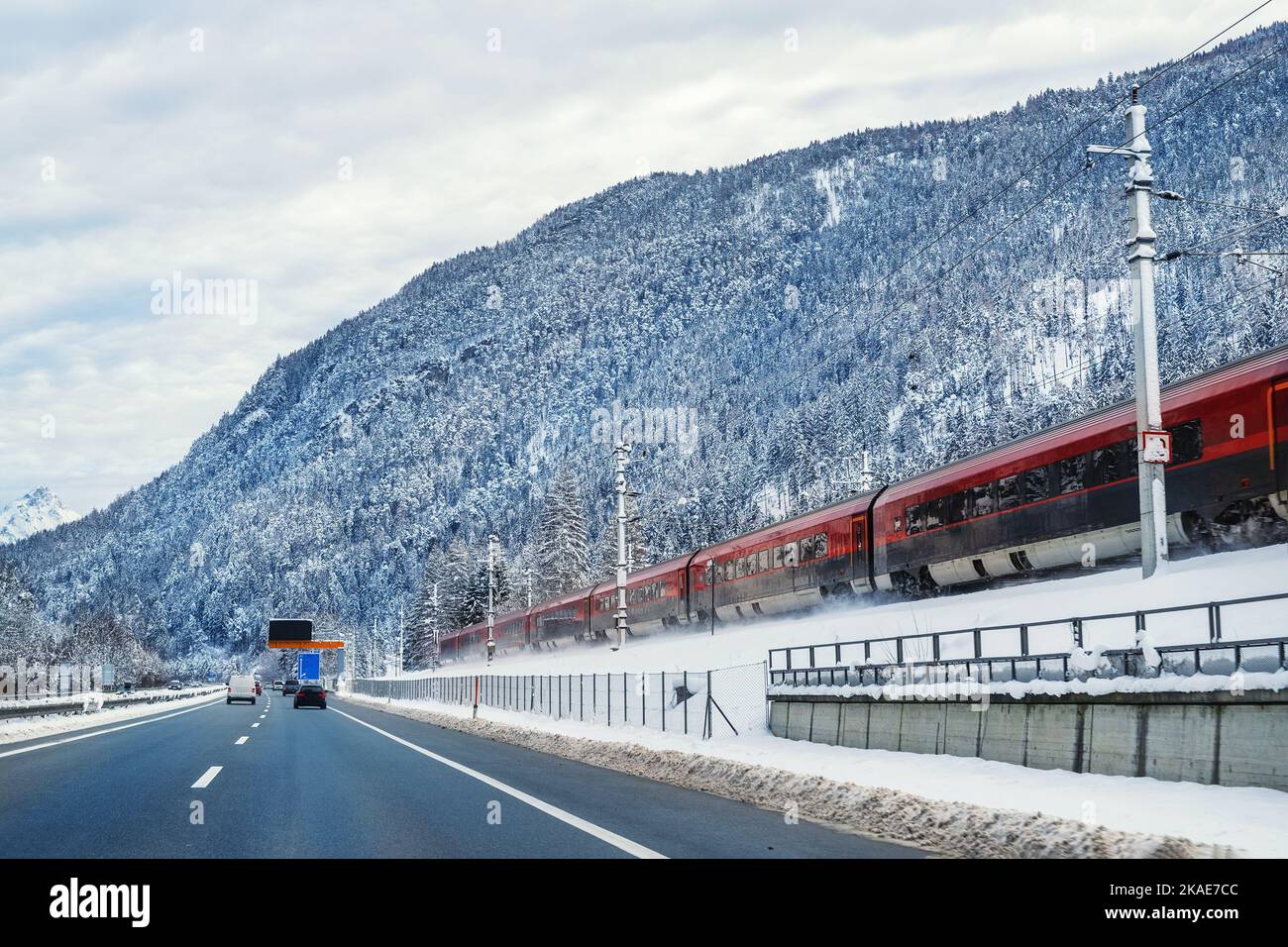 Winter alpine mountain highway and parallel railway road with intercity ...