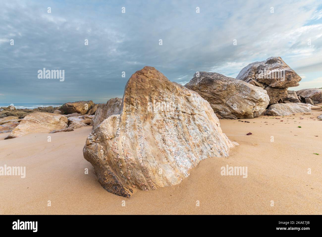 Rocks polished by waves of Atlantic Ocean on sandy beach. Sables d ...