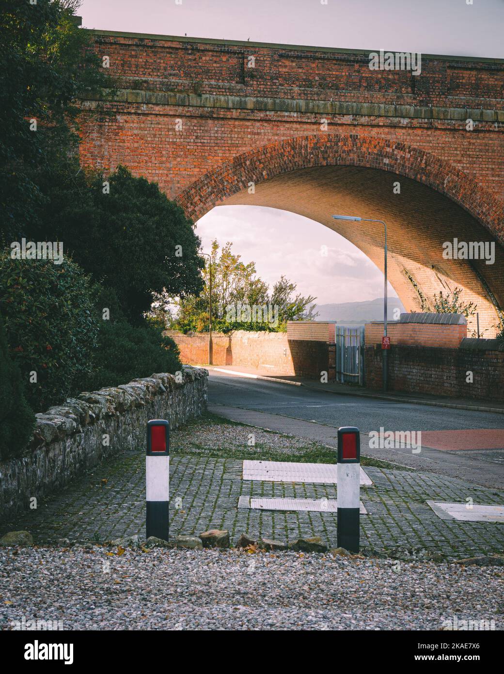 A paved road under the bridge made of brown bricks Stock Photo - Alamy