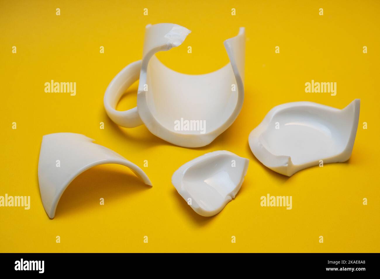 Splinters of the broken tea mug on a yellow background Stock Photo - Alamy