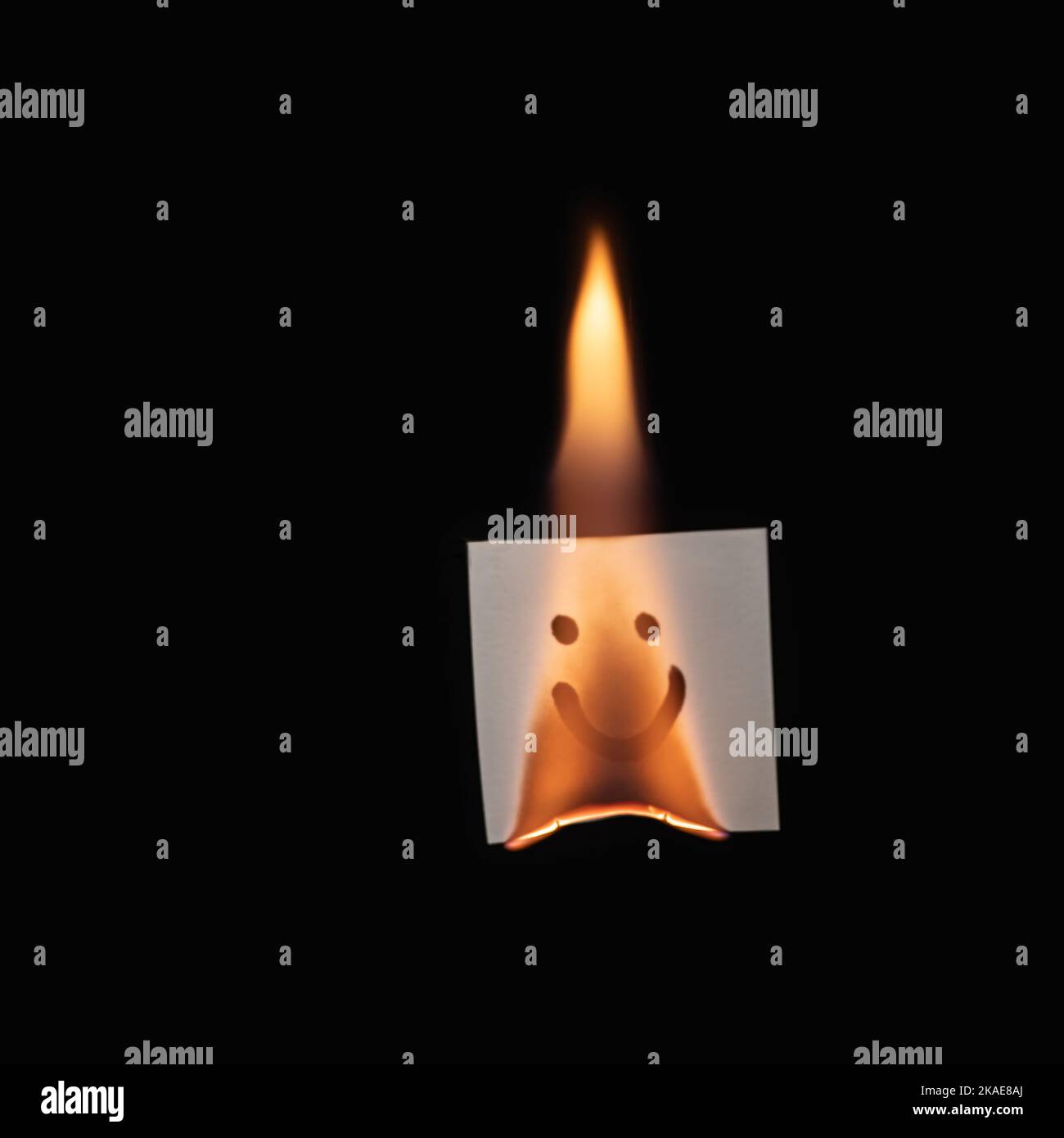 A small paper with smiley face sign burning on a black background Stock ...