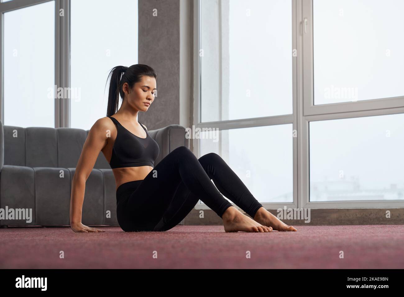 Side view of brunette girl meditating, doing yoga indoors. Young ...