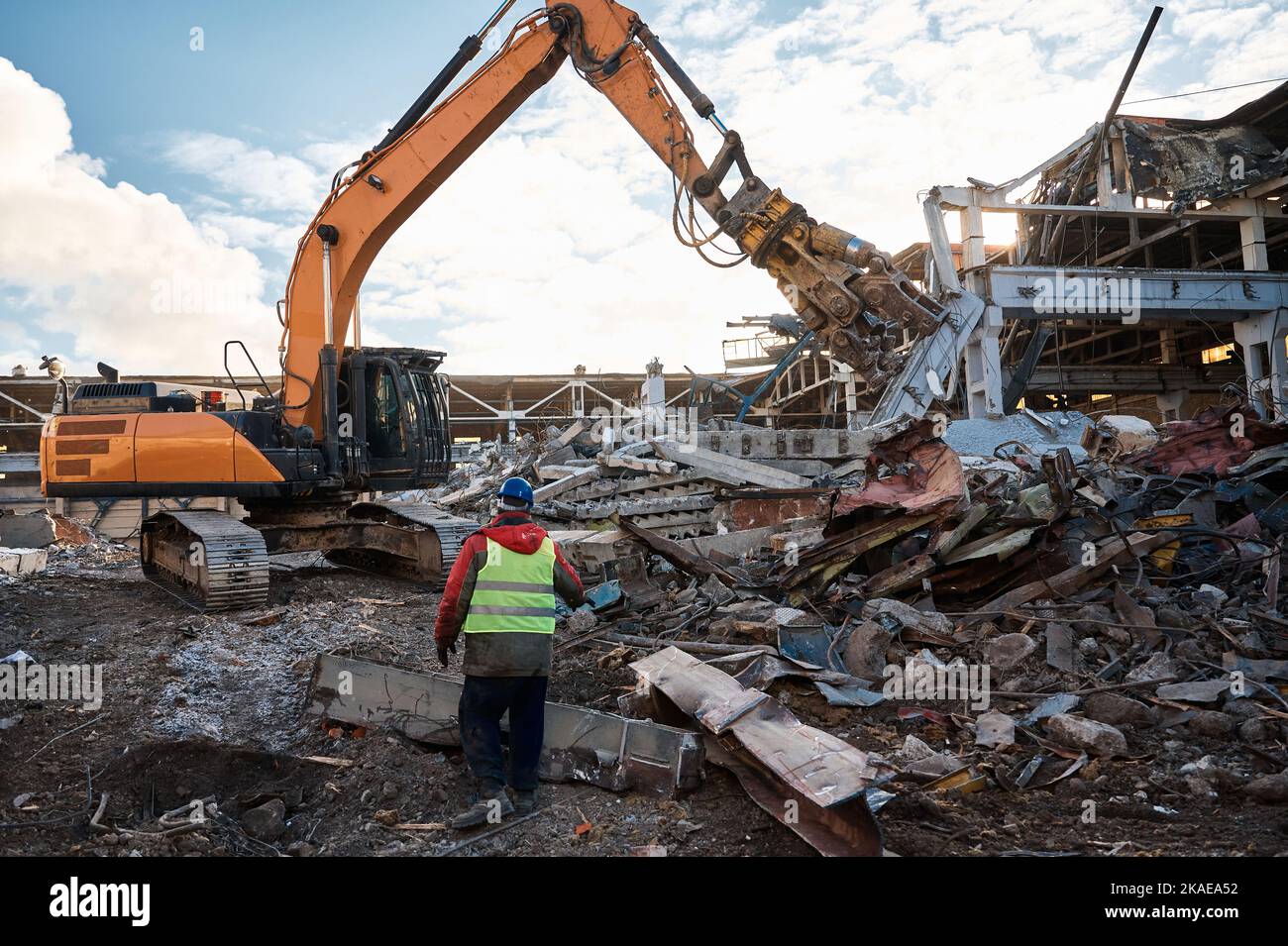 Excavator destroyer removes debris under worker control Stock Photo - Alamy