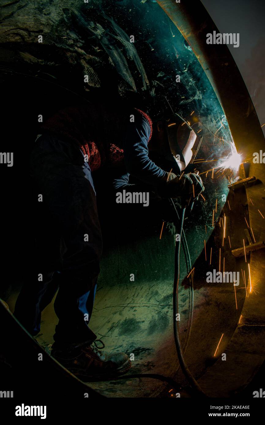 A vertical shot of a person in uniform welding in a dark tunnel Stock ...