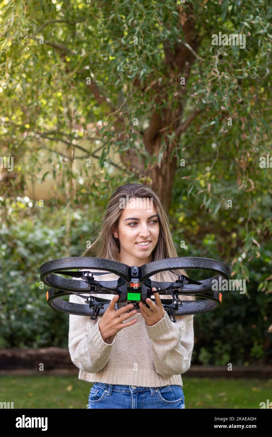 Vertical view of young woman smiling holding big drone in nature with ...