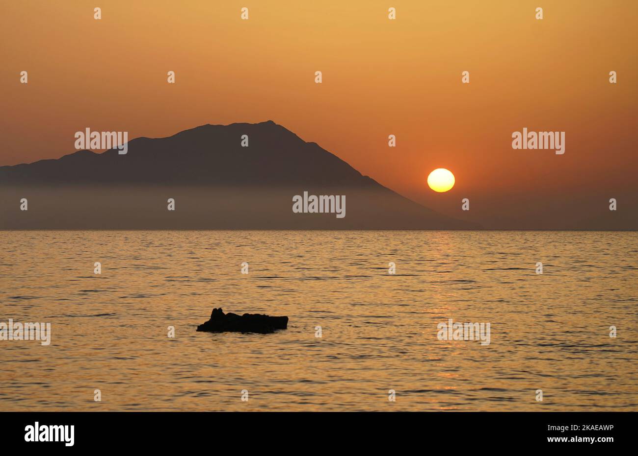 A silhouette shot of a floating object on the ocean during sunset with ...