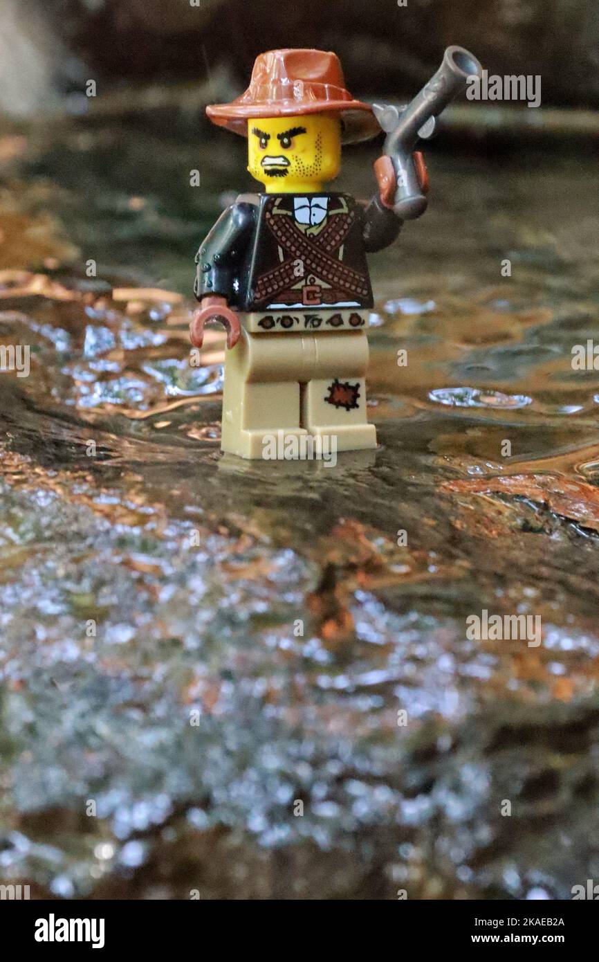 A vertical shot of an angry male cowboy Lego character with a gun ...