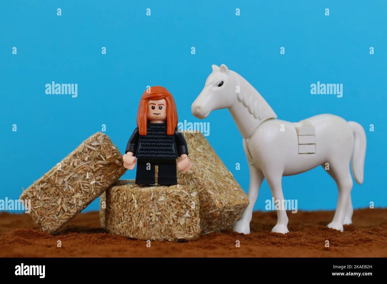 A red-haired farmer female Lego figurine standing on hay bales and a ...