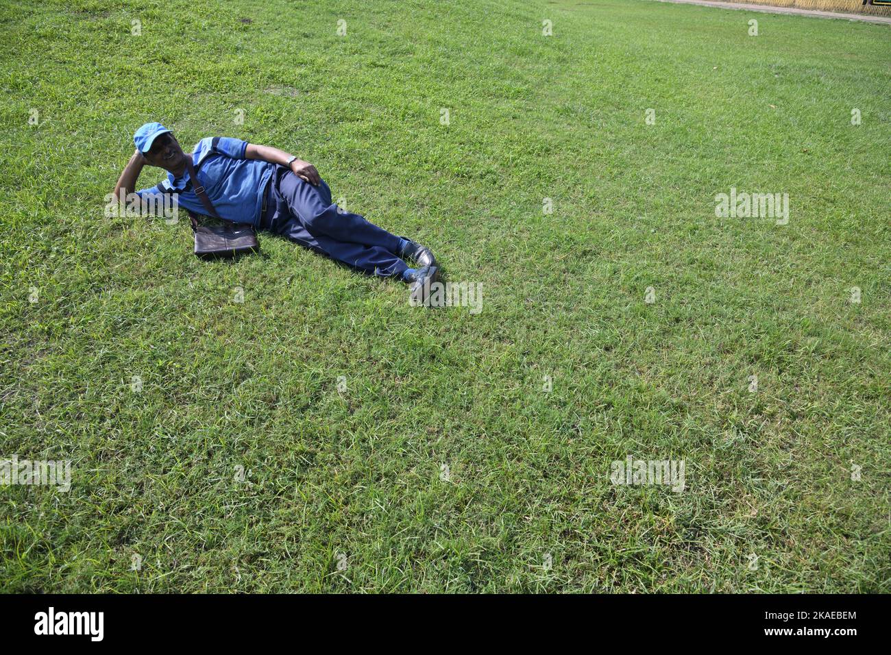 A visitor taking rest on a green grass field. AJC Bose Indian Botanic ...