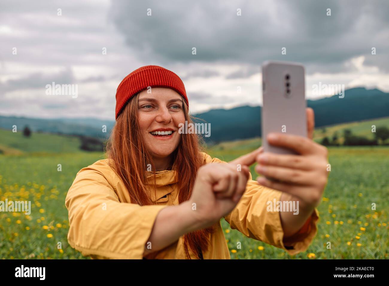 Happy traveler hiker girl taking photo on smartphone on top of mountain ...