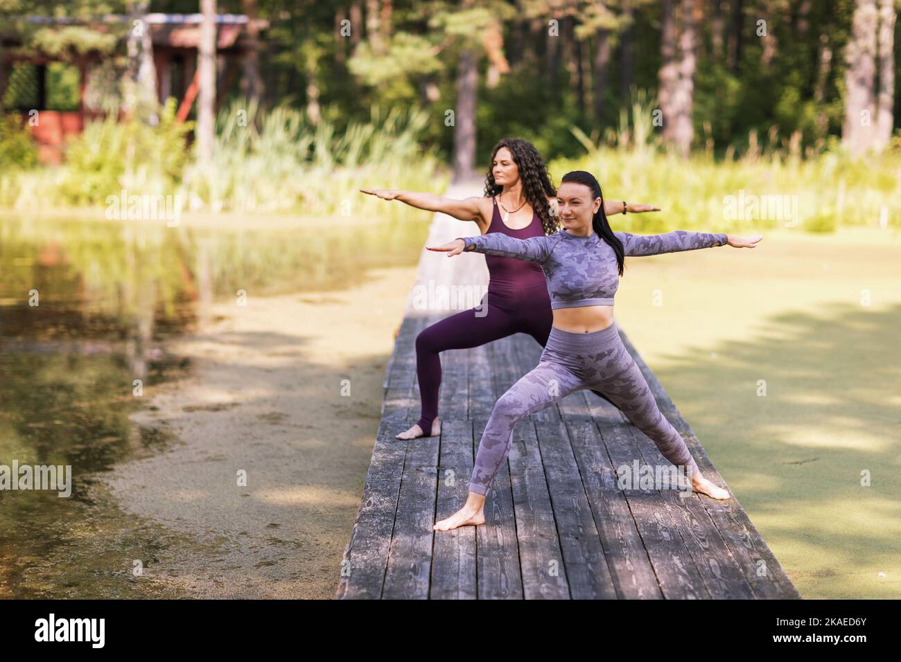 Two women practicing yoga, doing the exercise virabhadrasana, warrior ...