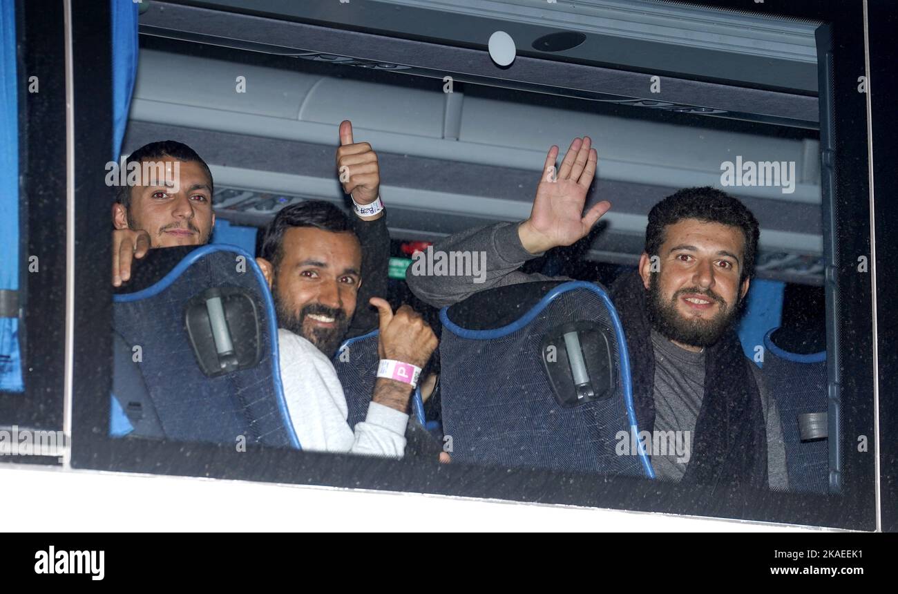 A group of people thought to be migrants gesture as they leave onboard ...