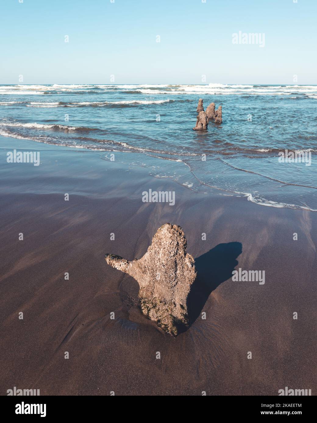 A vertical shot of sea waves washing the rocks on a sandy beach Stock ...