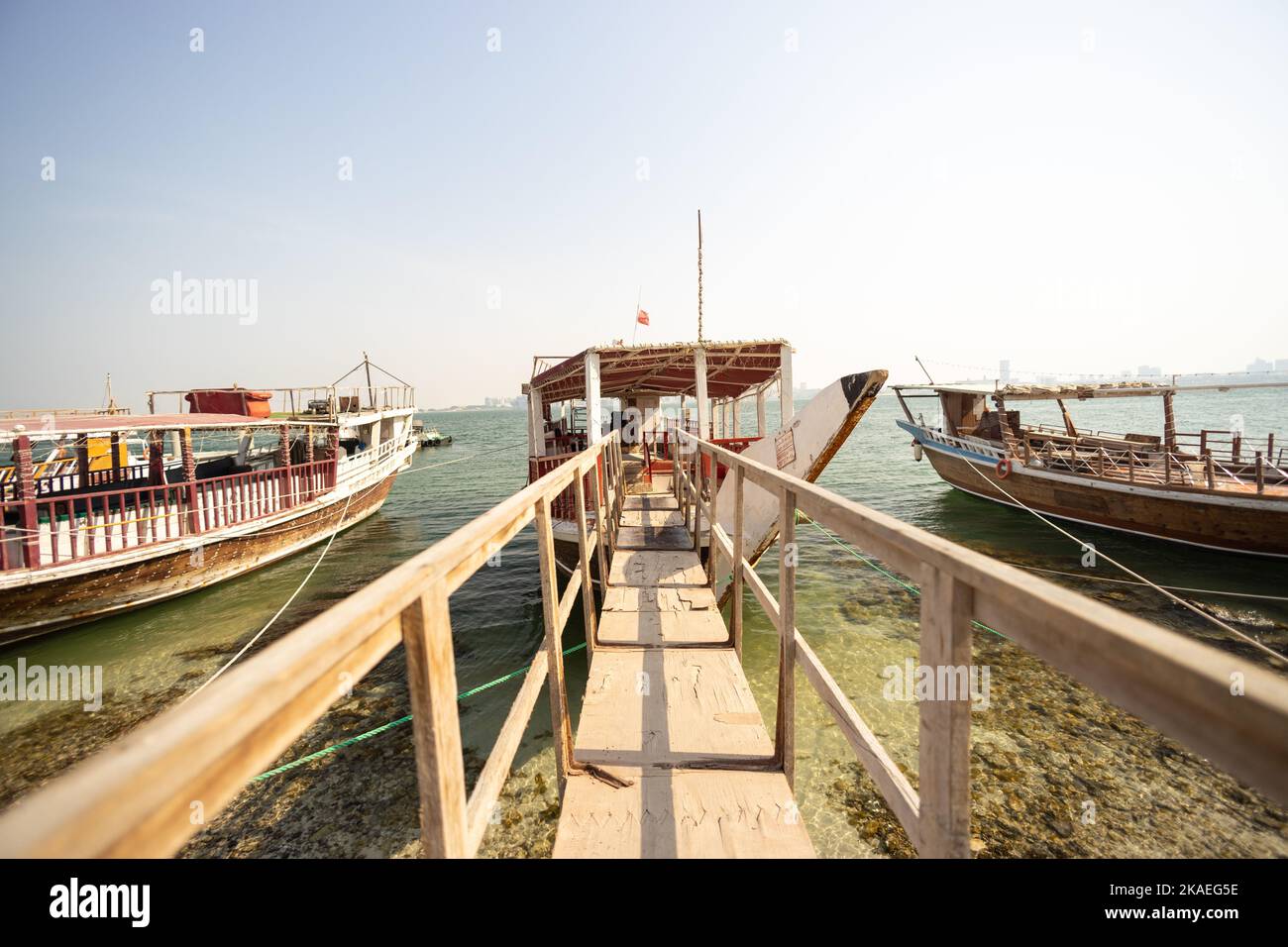 A row of empty old traditional dhow ships docked by the shore at Doha ...