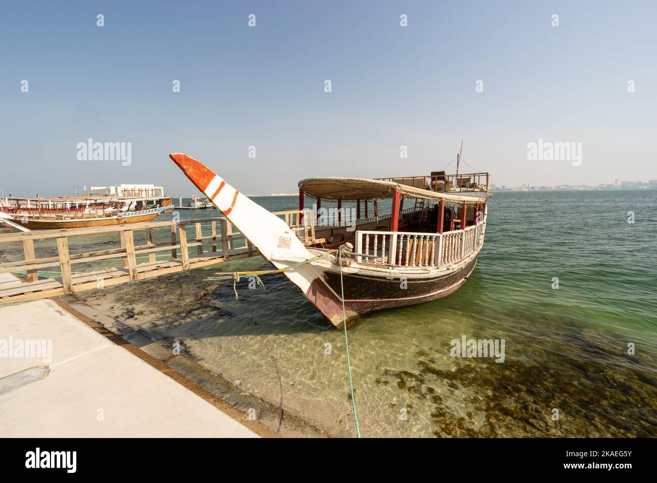 An empty old traditional dhow ship docked by the shore at Doha Port ...