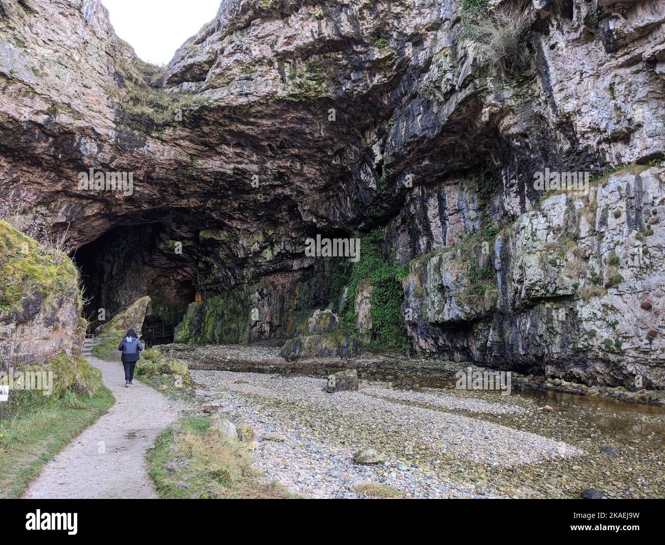 A man entering a the big rocky cave Stock Photo - Alamy