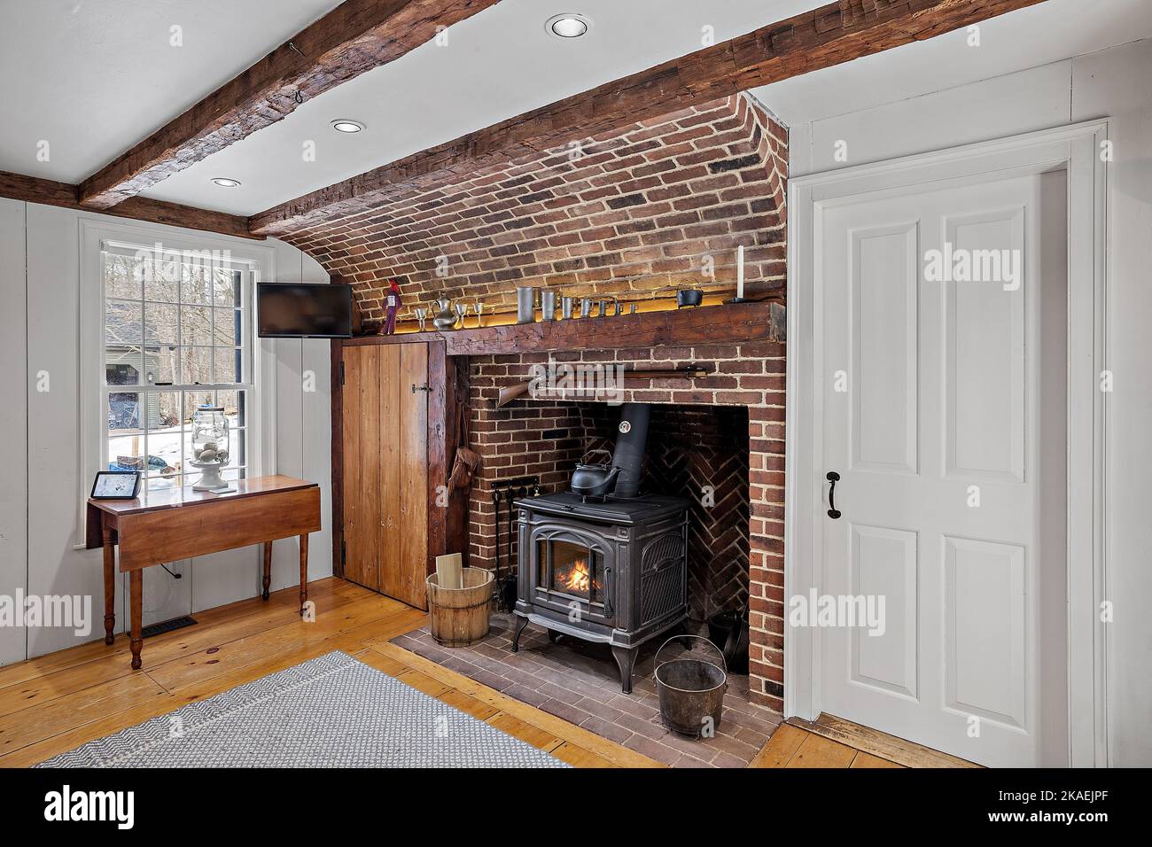 A wood stove in a brick fireplace in a cozy room decorated in vintage ...