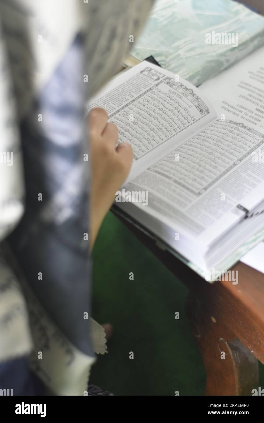 A vertical shot of an opened book laid on a table with a Muslim woman ...