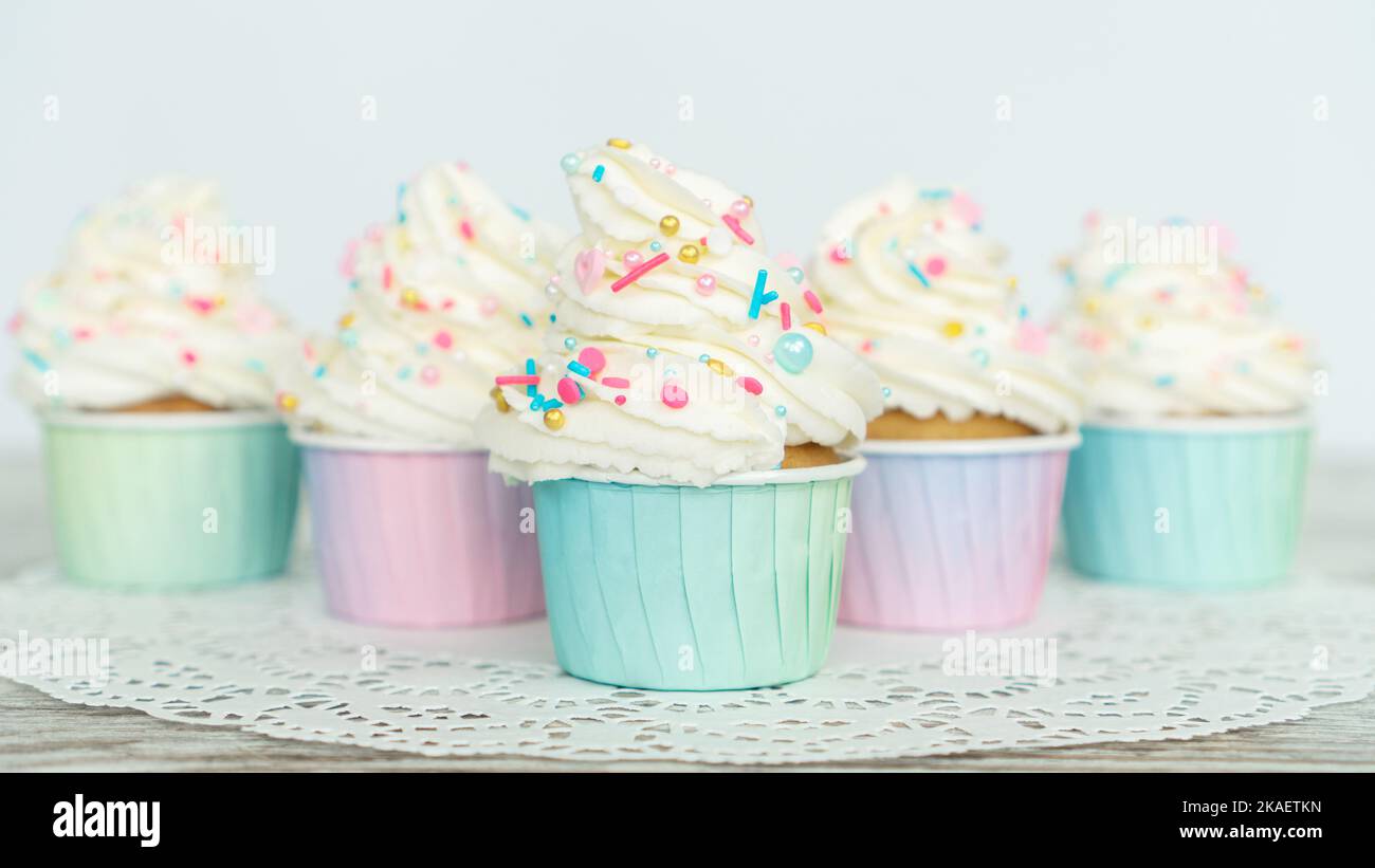 A set of vanilla cupcakes with golden sprinkles. Festive buttercream ...