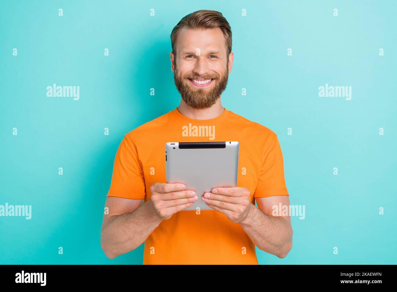 Photo of optimistic beard guy hold tablet wear orange t-shirt isolated ...