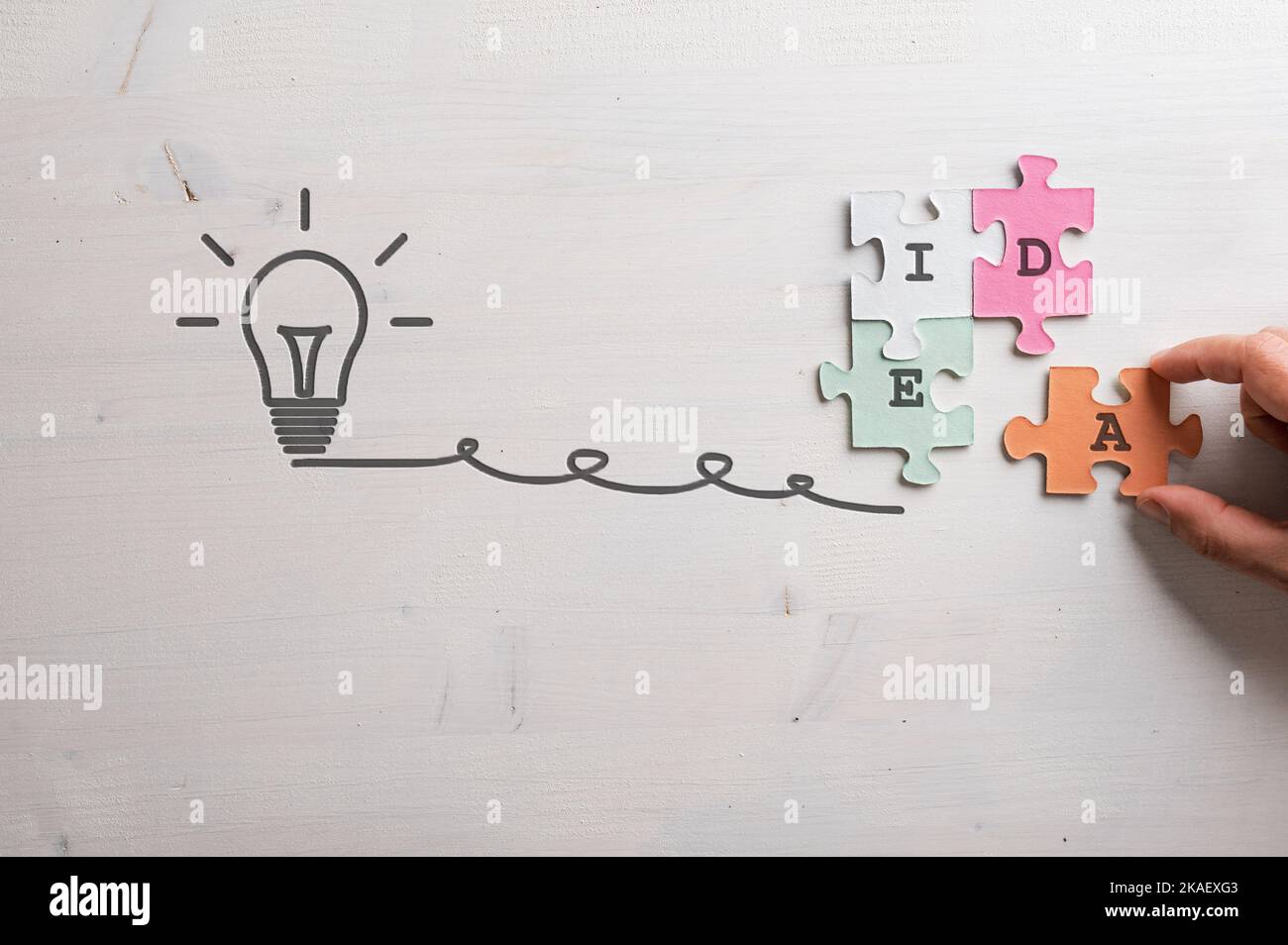 Male hand assembling four colorful matching puzzle pieces to spell the ...