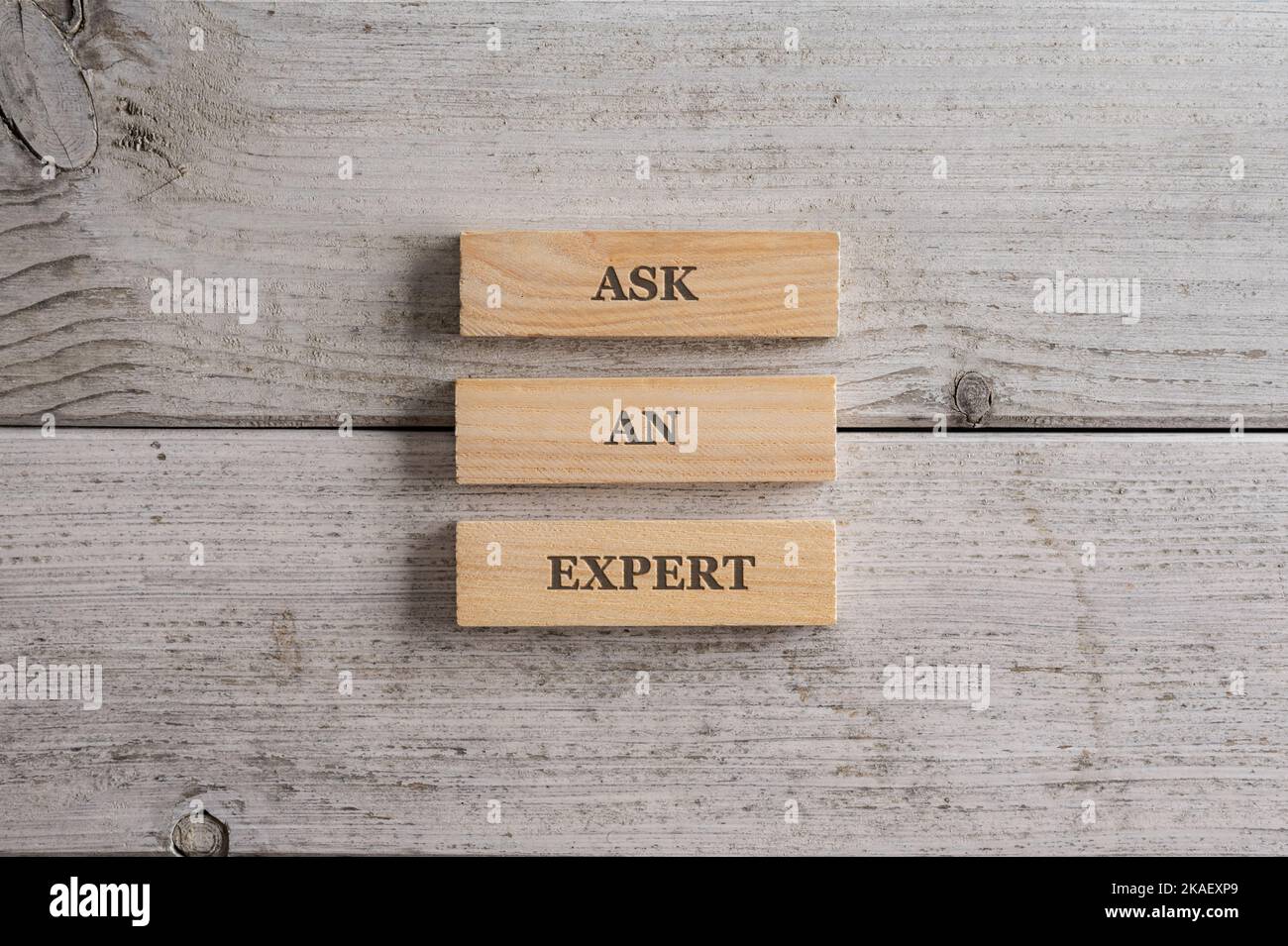 Ask an expert sign written on three stacked wooden pegs placed over ...