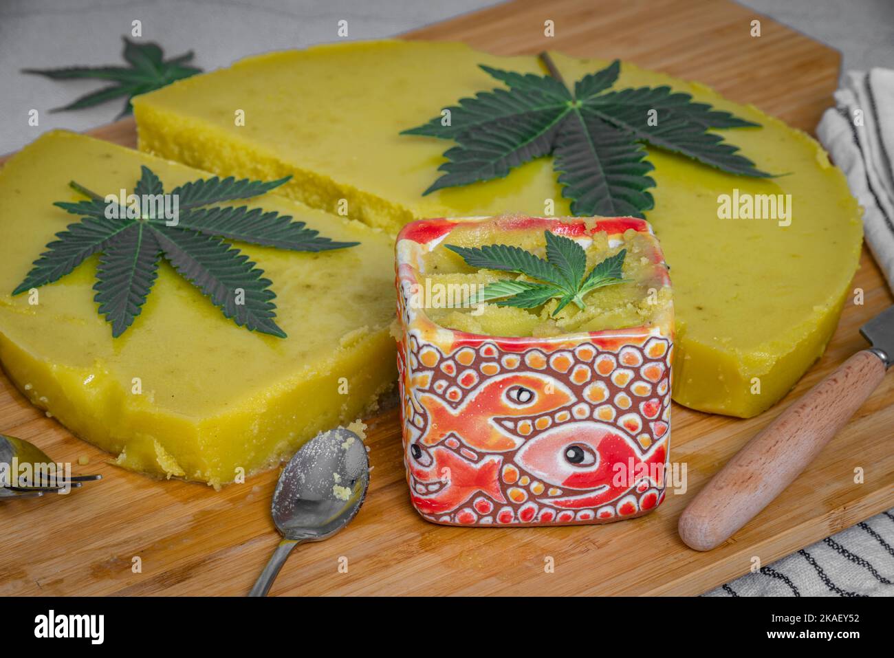Yelllow marijuana butter on light stone table with dish towel and color ...