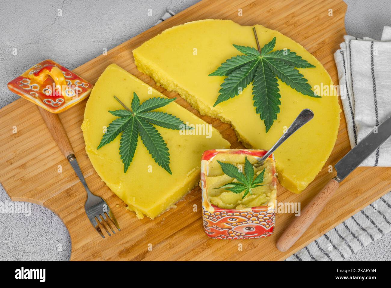 Yelllow marijuana butter on light stone table with dish towel and color ...