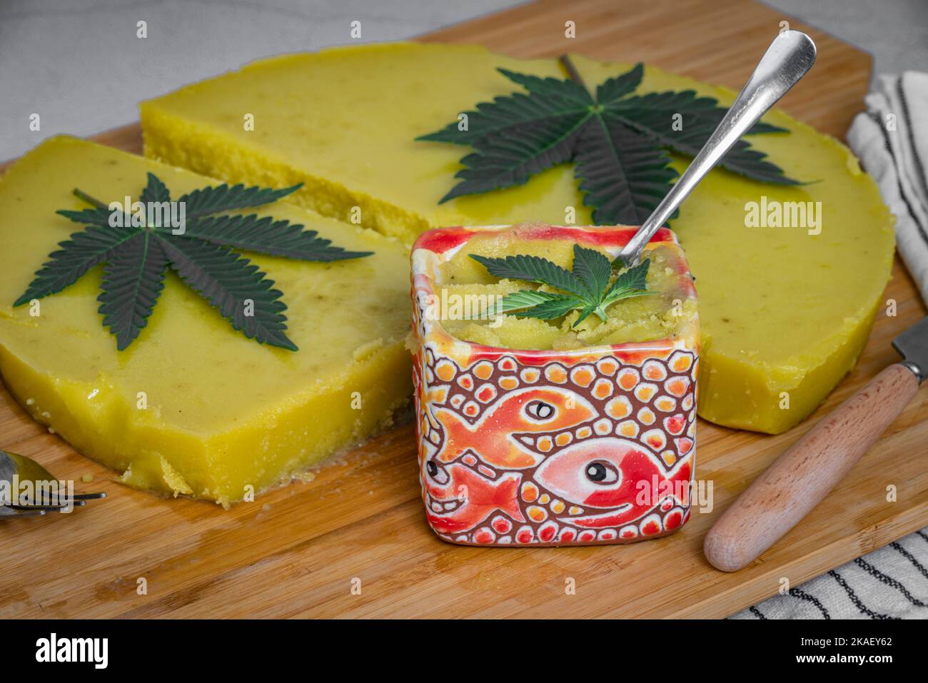 Yelllow marijuana butter on light stone table with dish towel and color ...