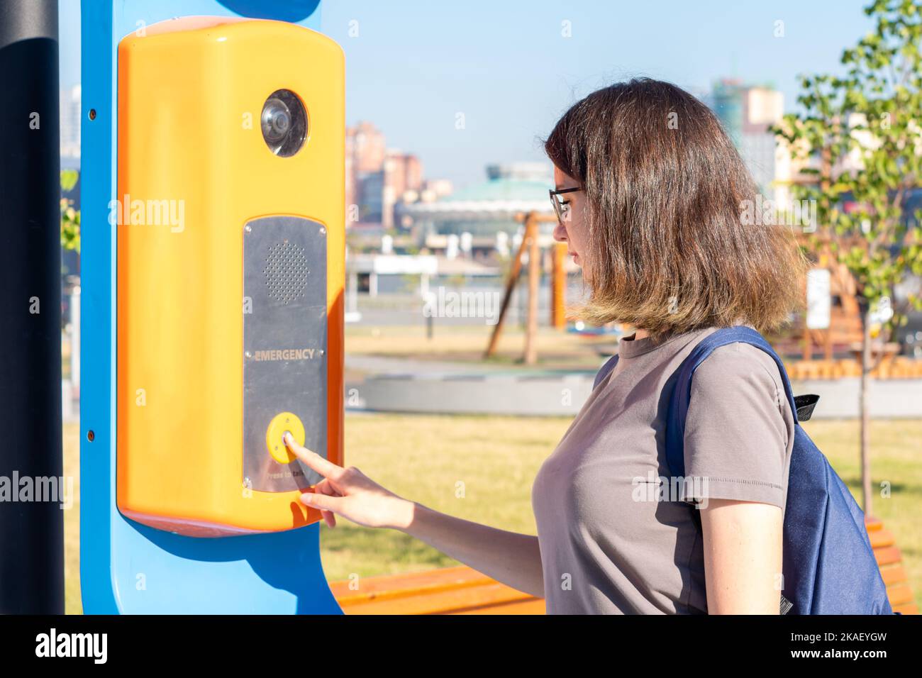 A student girl with a backpack presses the emergency terminal help ...