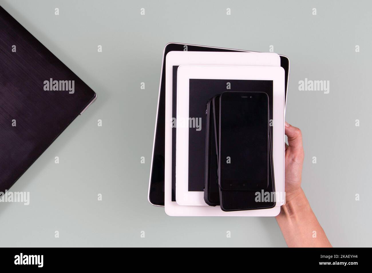 Woman hand holding pile of digital tablet computers and smartphones ...