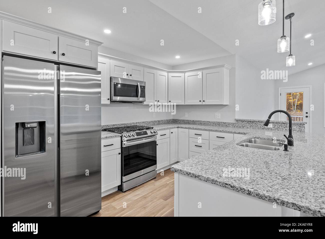 A newly renovated kitchen with hardwood floors, white furniture, silver ...
