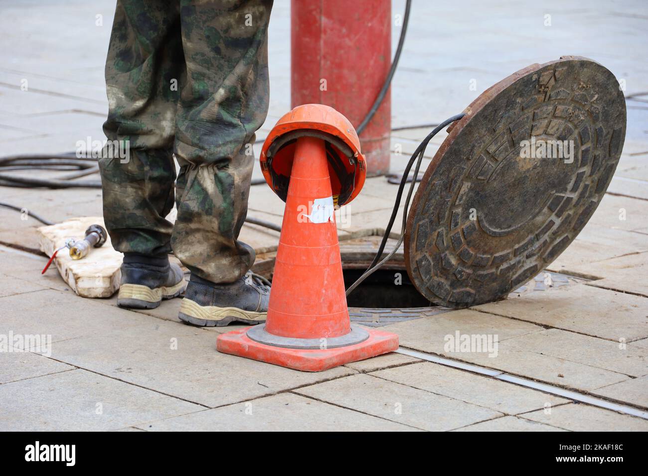 Worker standing over the open sewer hatch on a street. Concept of ...
