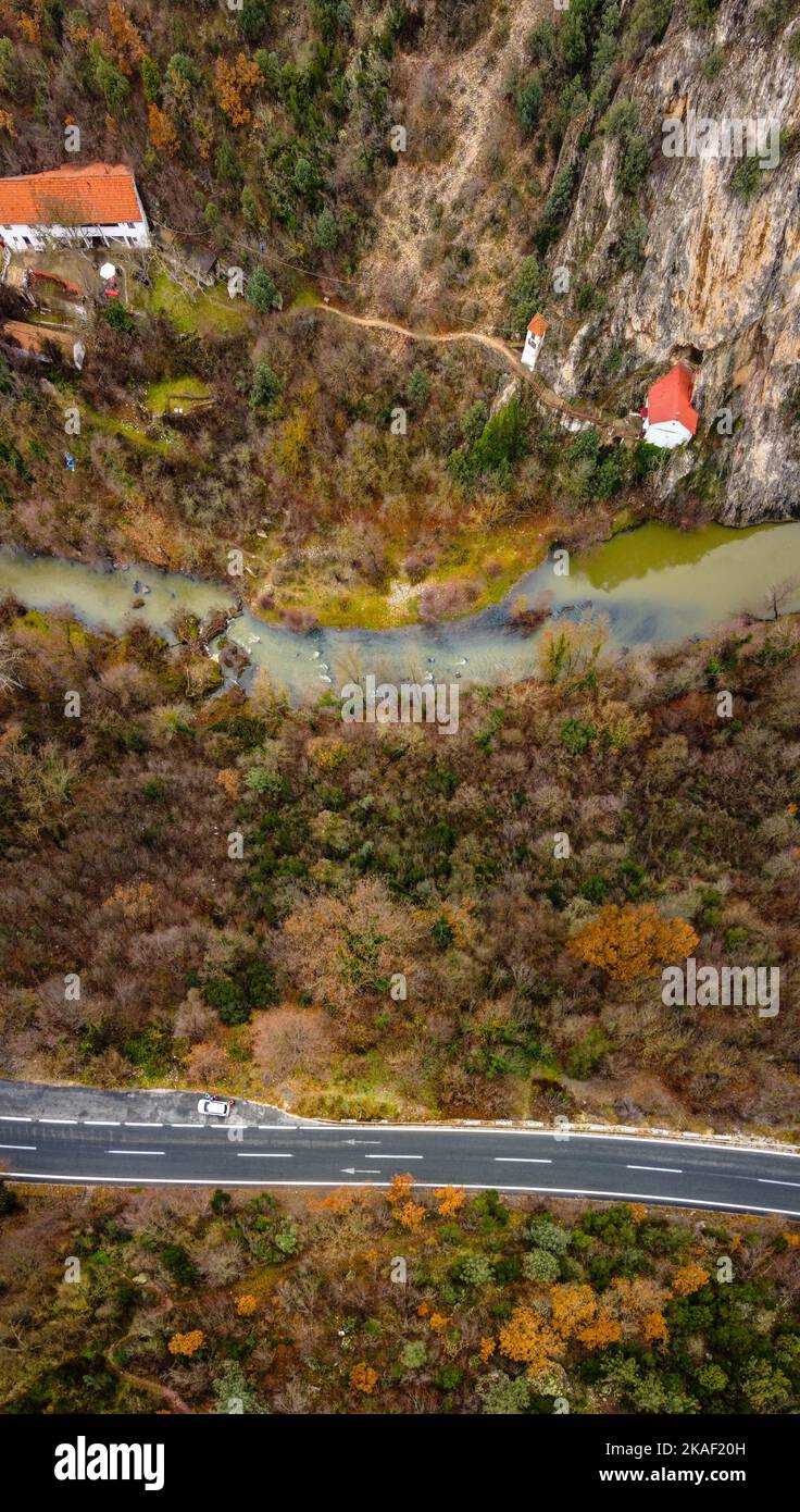 A vertical aerial view of asphalt road on the hill surrounded by ...