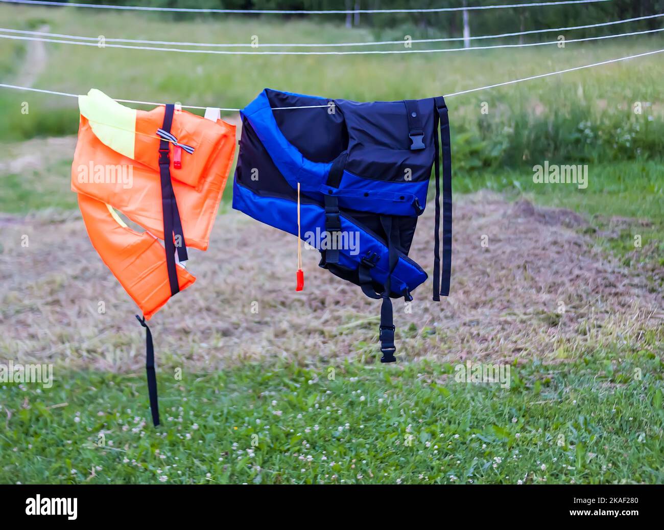 Orange and dark blue life jackets drying on the rope outdoors Stock ...