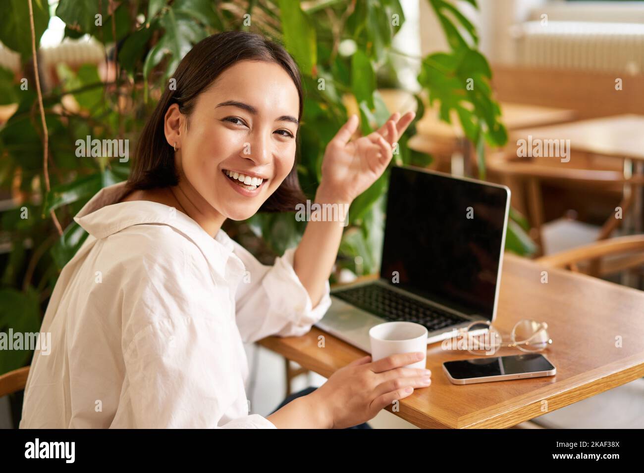 Portrait of beautiful young woman wave at you, say hello, greeting ...