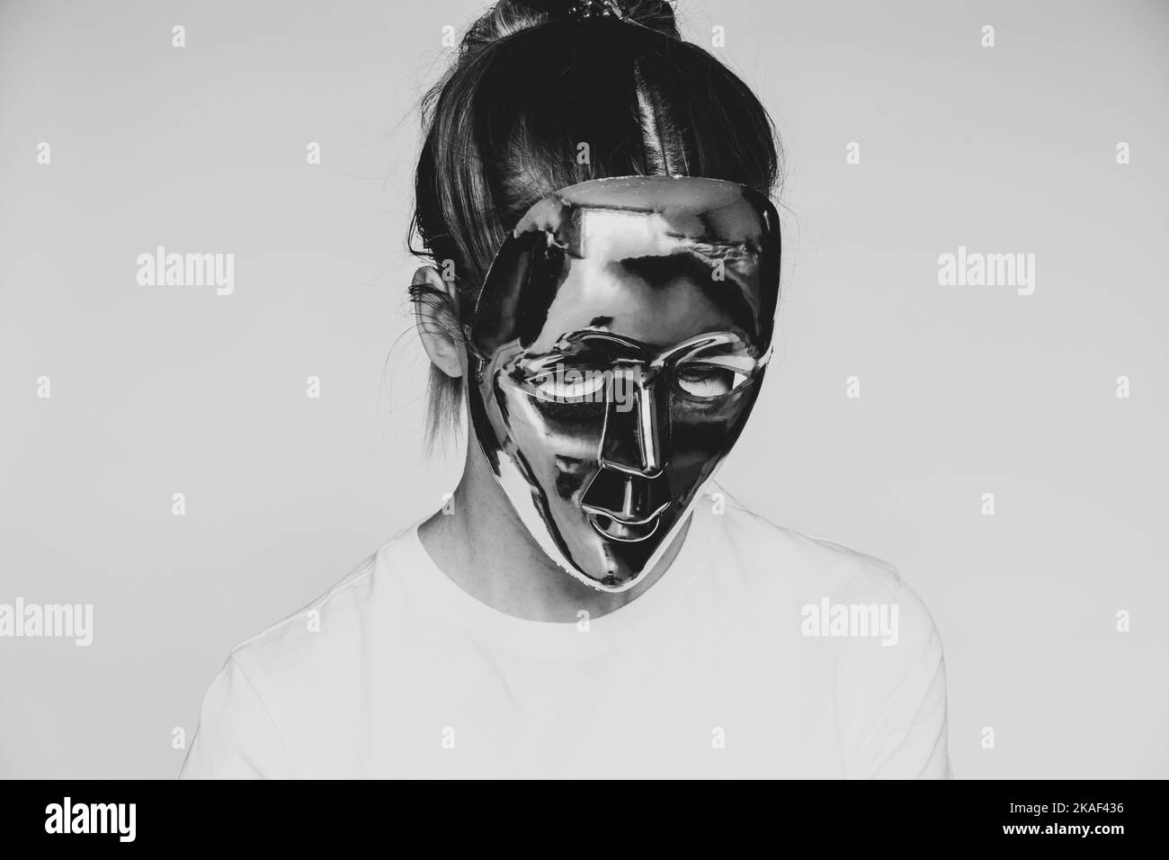 A girl in a faceless plastic mask bowed her head down on a white ...