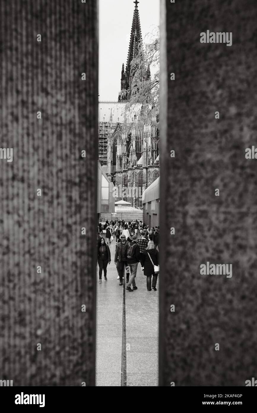 A greyscale shot of the Cologne Cathedral between two stone columns in ...