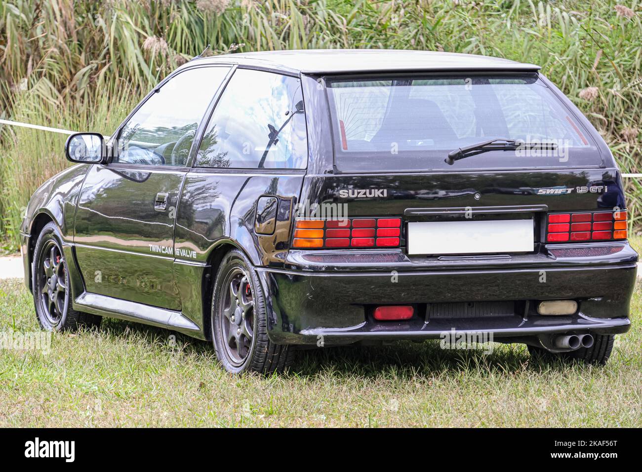 A classic black sports car Suzuki Swift 1.3 Gti Twin Cam 16V standing on the green grass Stock ...
