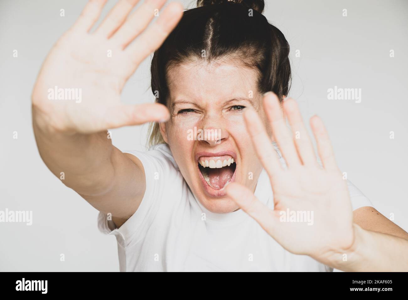 The girl screams and covers her face with her hands isolated background close-up, evil and ...