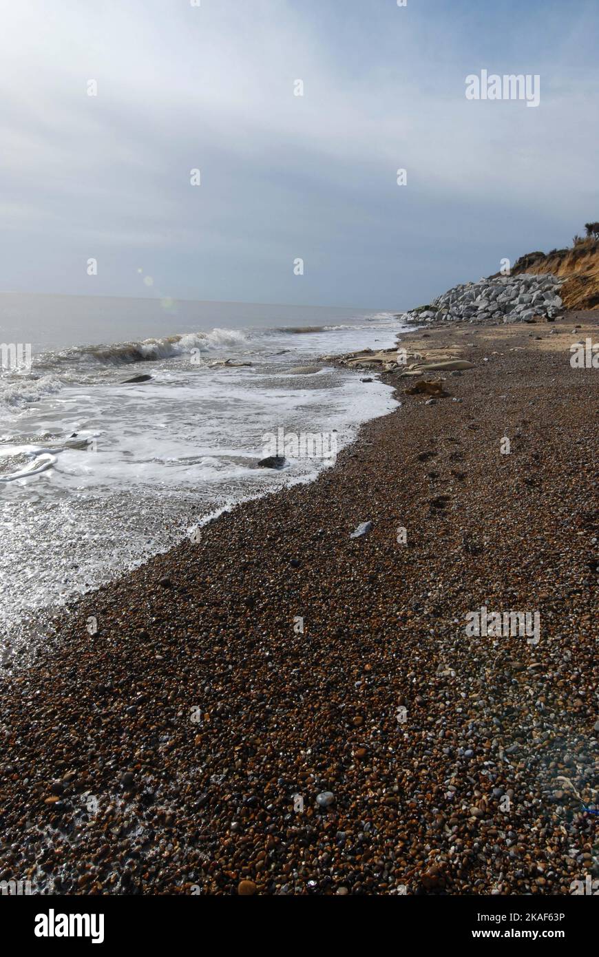 Waves breaking on shoreline with granite rock revetment flood defence ...