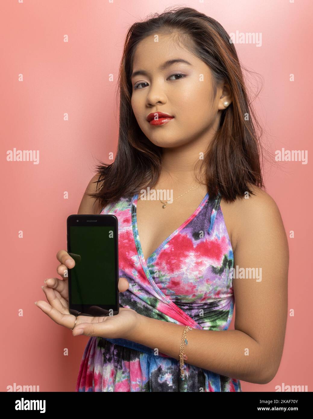 A beautiful Filipina in a colorful dress smiling and marketing a phone ...