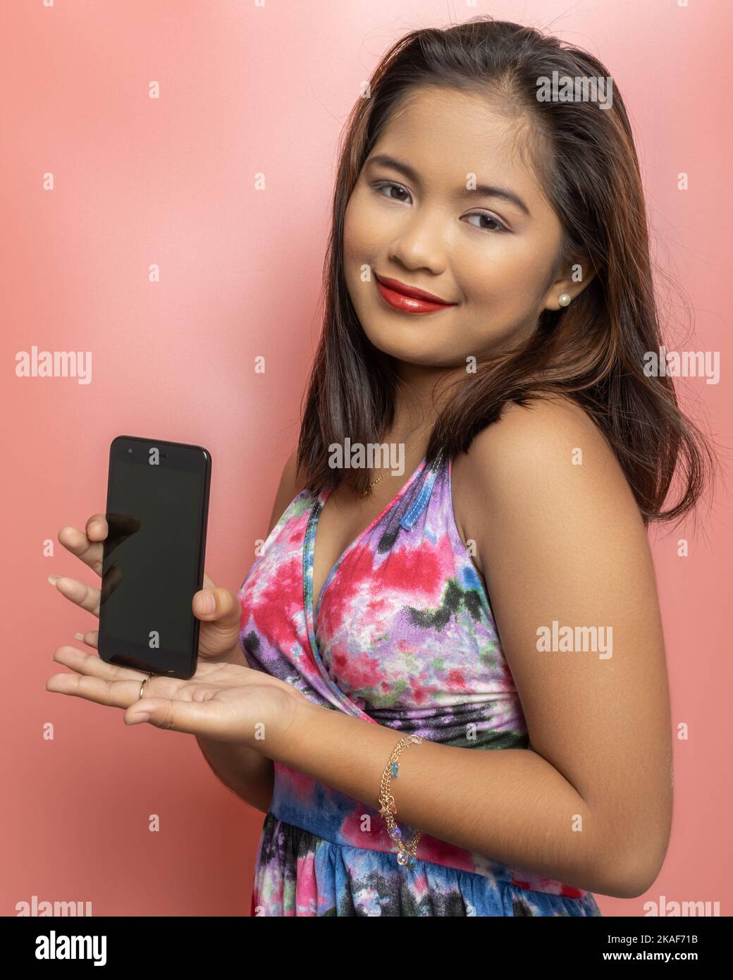 A beautiful Filipina in a colorful dress smiling and marketing a phone ...