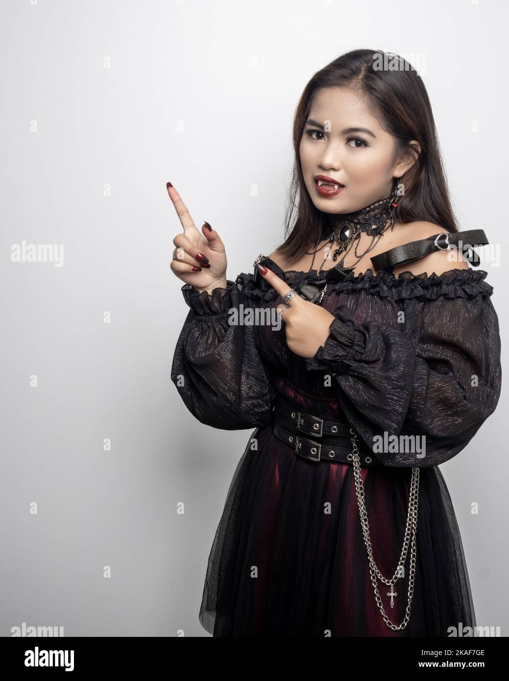 A Filipina in a vampire costume pointing to the side with index fingers ...