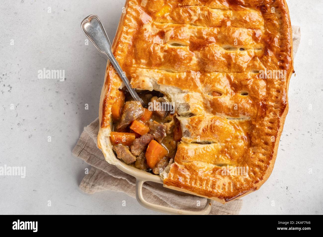English beef steak pie with crispy puff pastry close-up in a baking ...