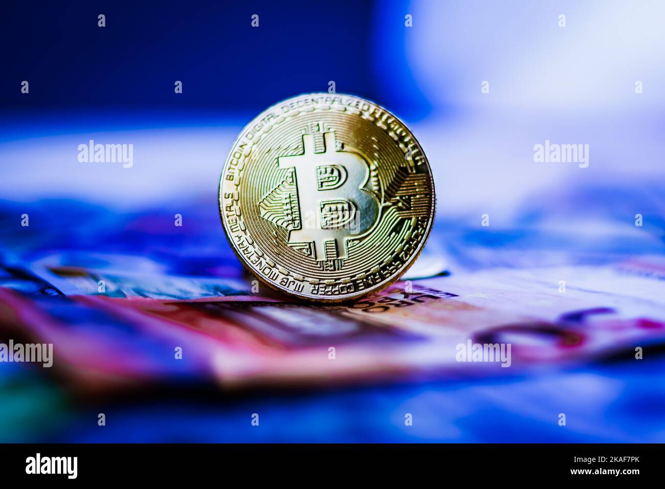 A closeup of a Bitcoin gold coin in a selective focus with banknotes on ...