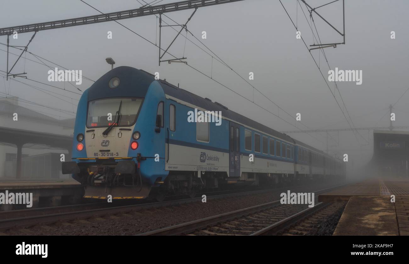 Commuter blue electric train in Kolin station in mist autumn cold ...