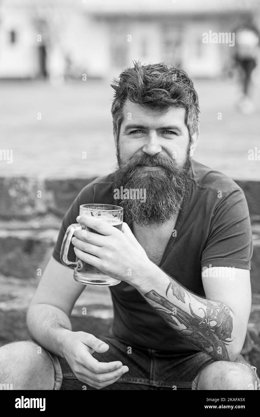 Hipster with long beard looks relaxed. Bearded hipster holds beer mug ...
