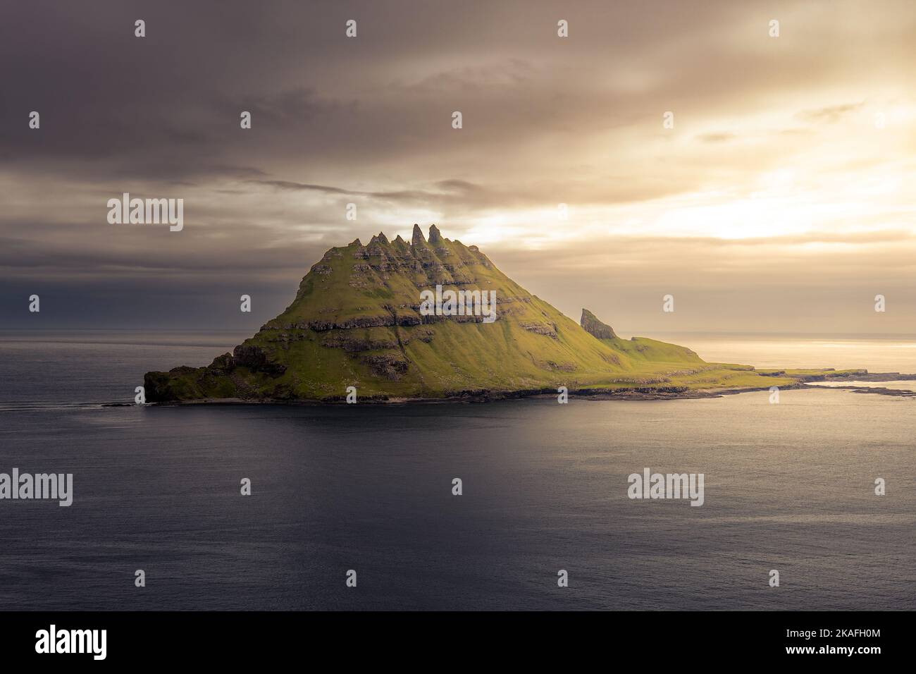 A green, small island with huge cliffs and rocks at sunset Stock Photo ...